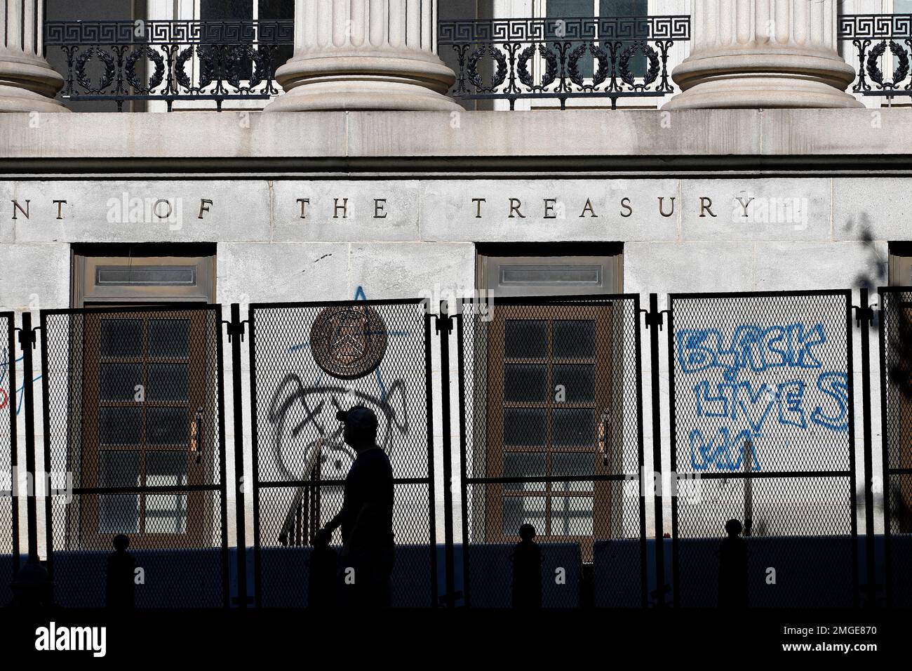 A man walks past security fencing outside the Treasury Building, Sunday ...