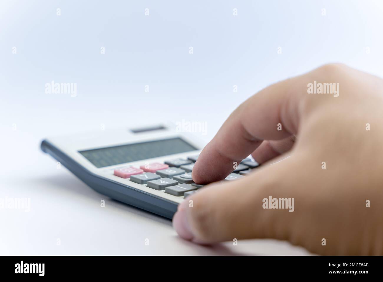 Hand calculating with a white digital calculator isolated on white ...