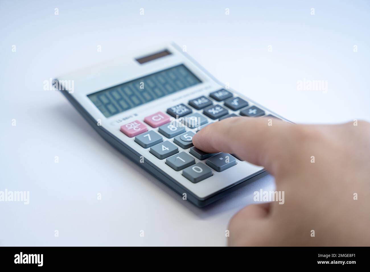 Hand calculating with a white digital calculator isolated on white ...
