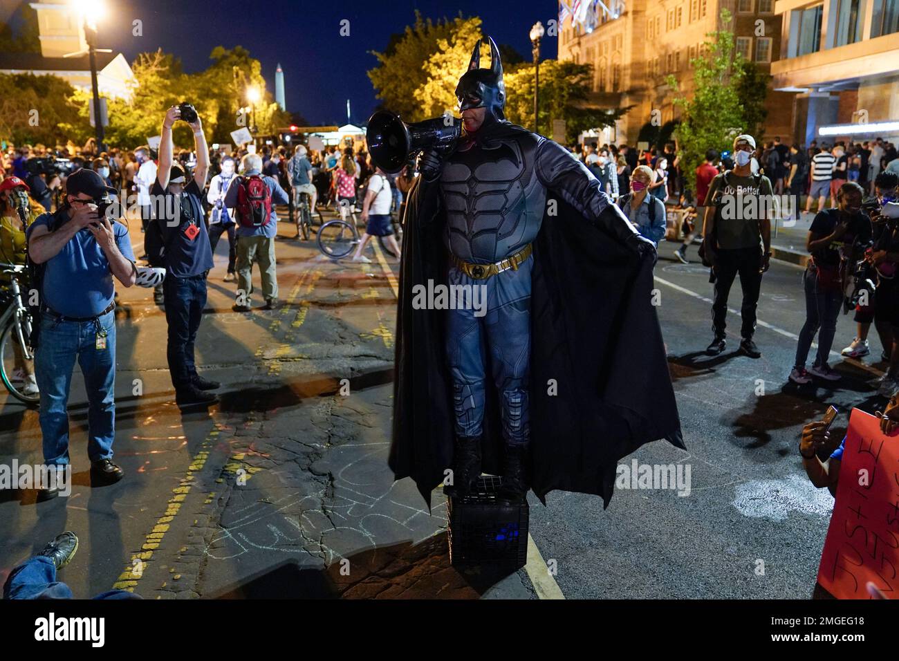 A demonstrator dressed as Batman speaks as protests over the death of ...