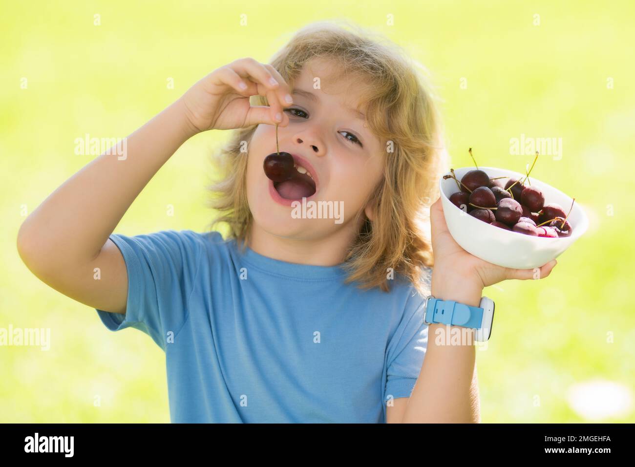 Cherry and cute child. Happy little child with cherry outdoors. Kid ...