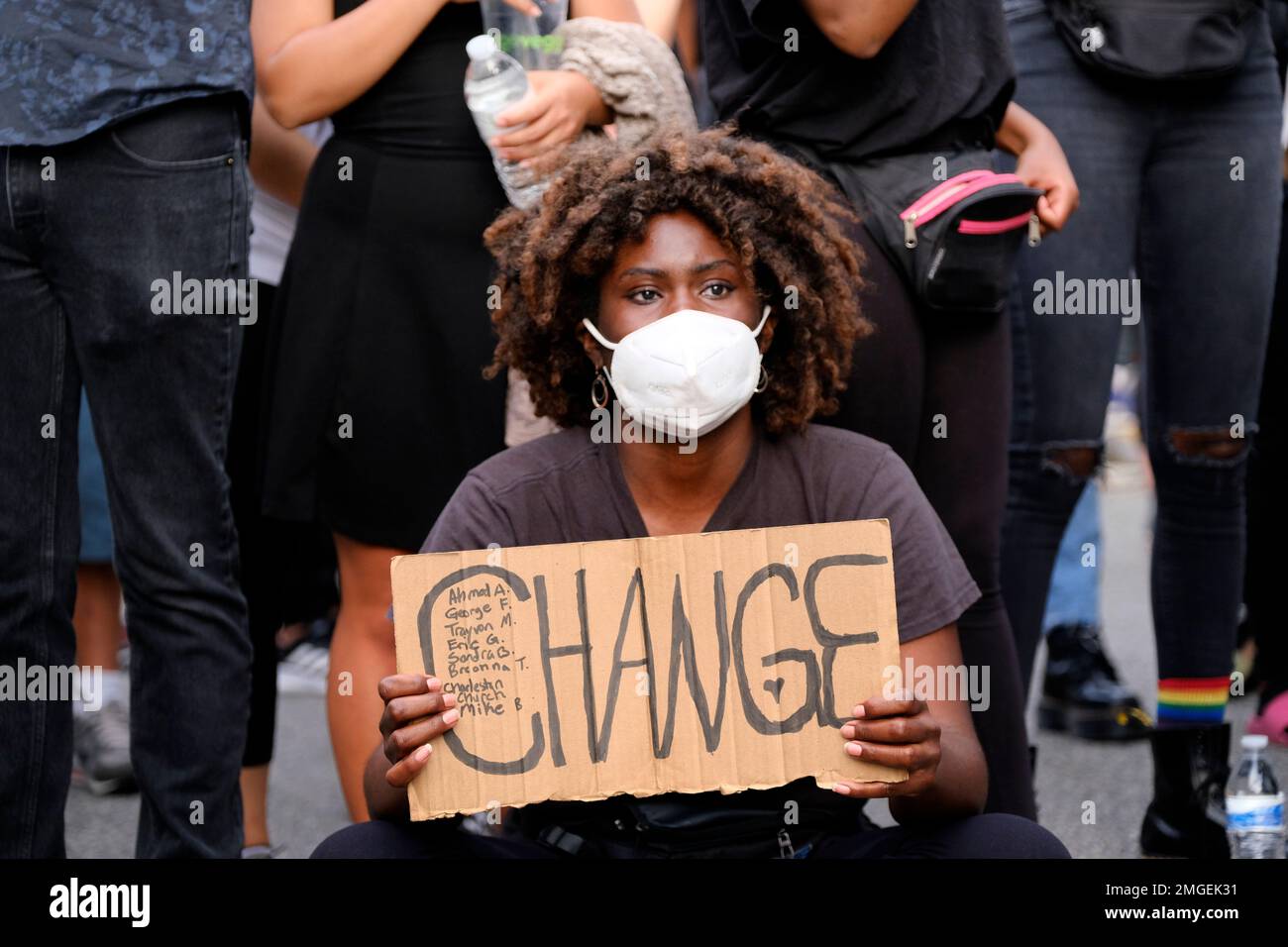 A Black Lives Matter protester sits and holds a sign for change outside ...