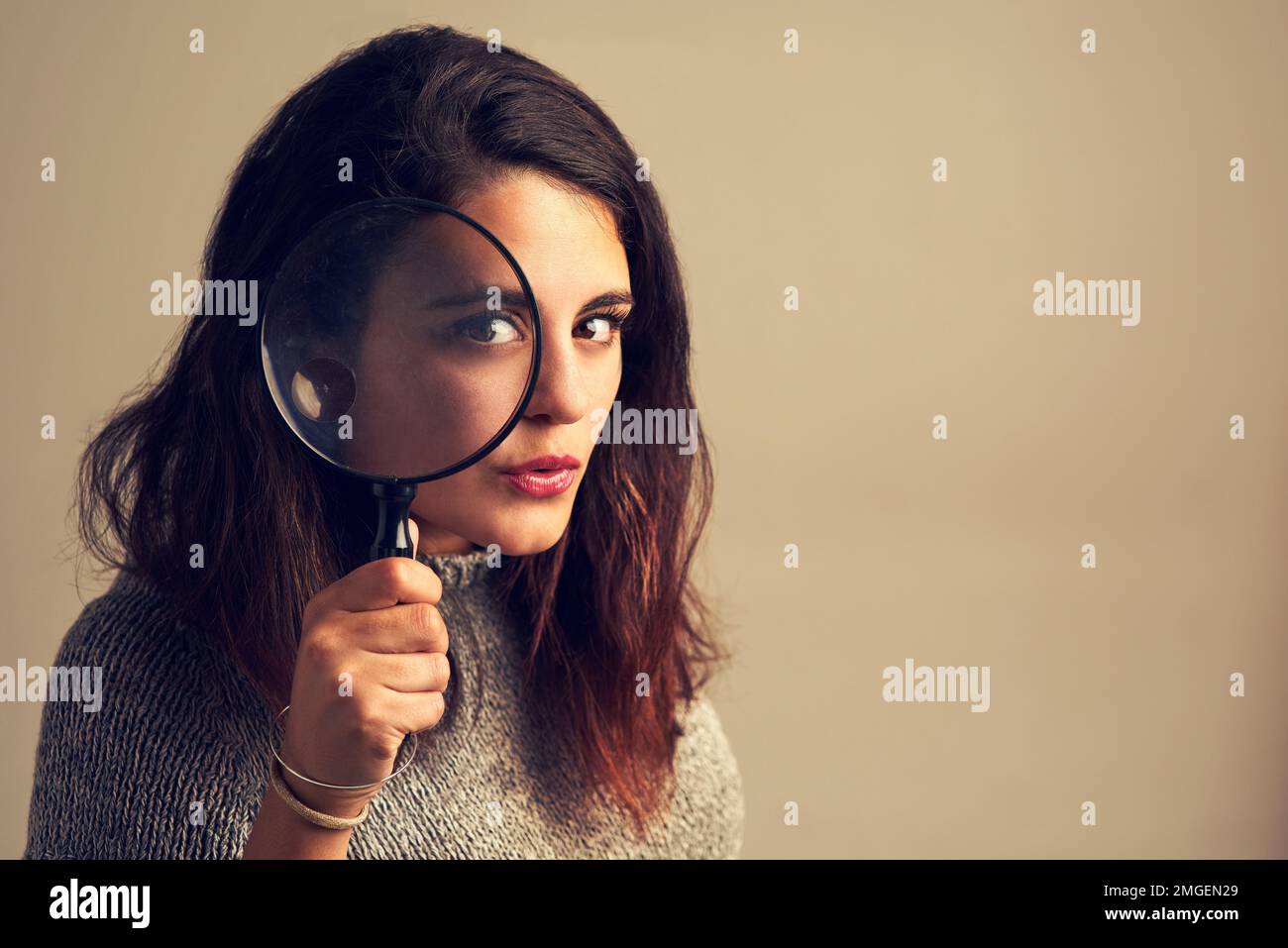 Yes, I see you there. Studio portrait of a young woman looking through ...