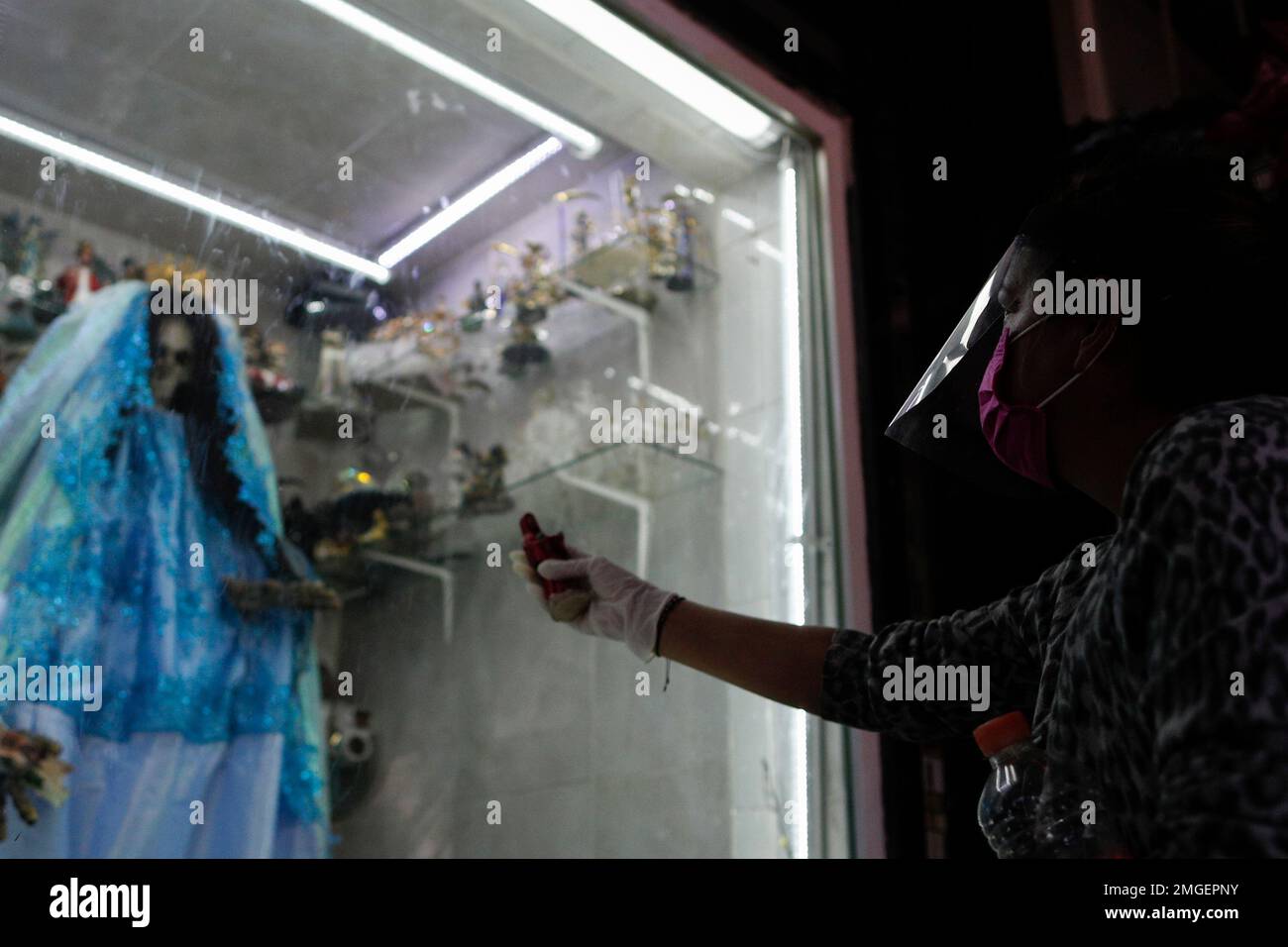 A devotee wearing a face mask and shield pays her respects to the ...