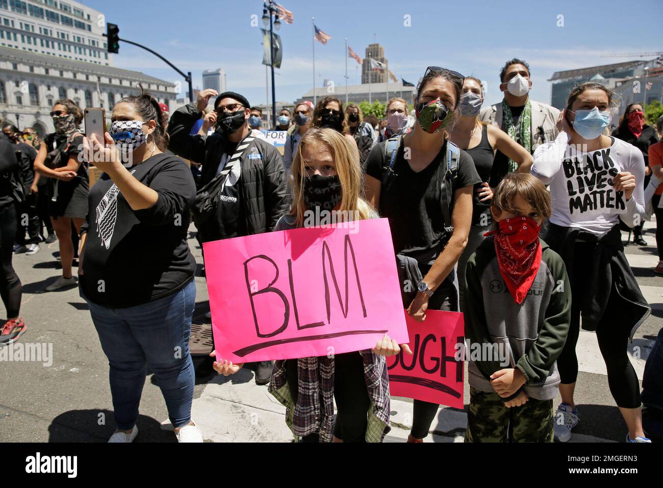 People hold signs and listen to speakers during a "kneel-in" to protest ...