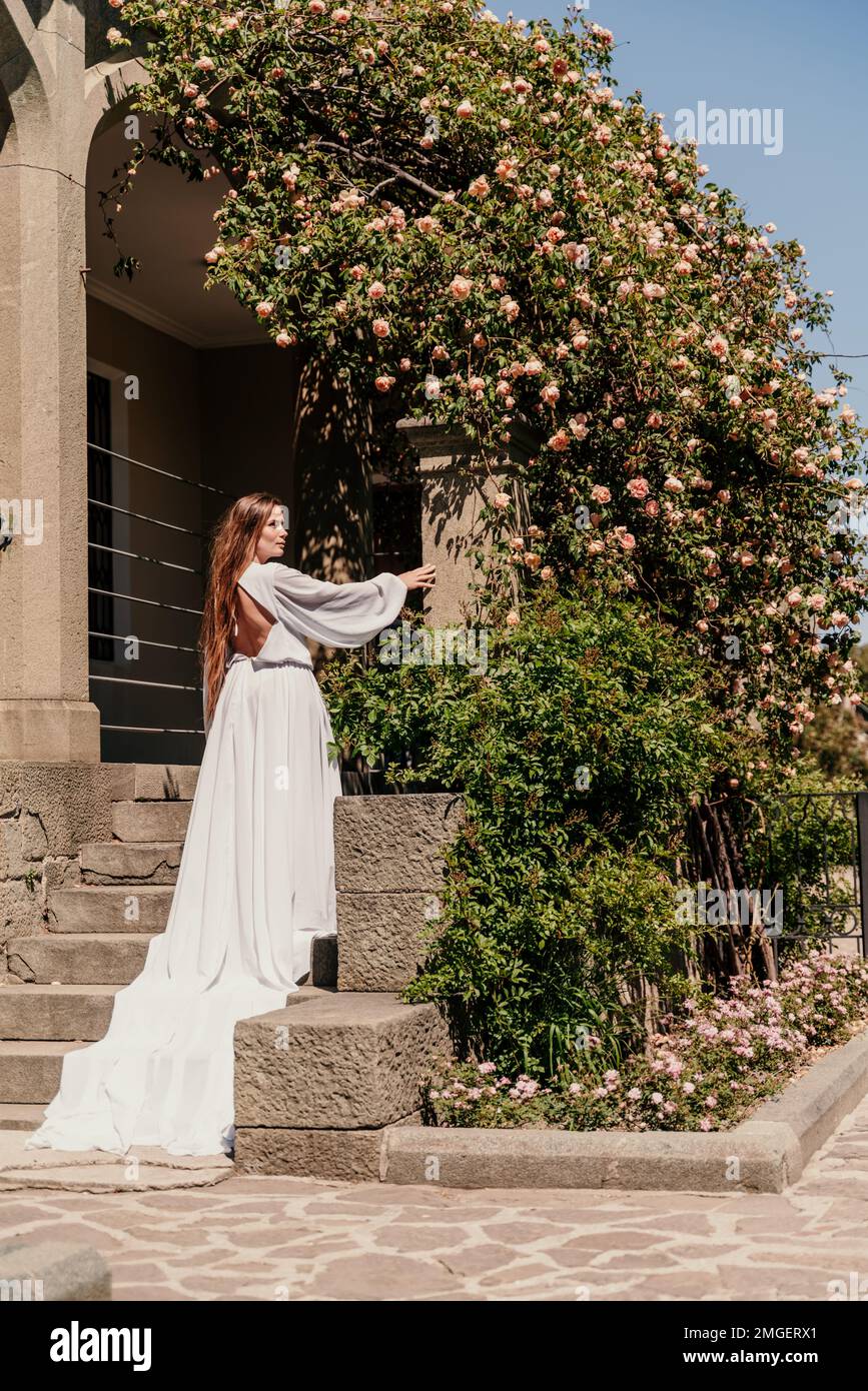 a beautiful woman in a white flowing long dress stay near a beautiful ...