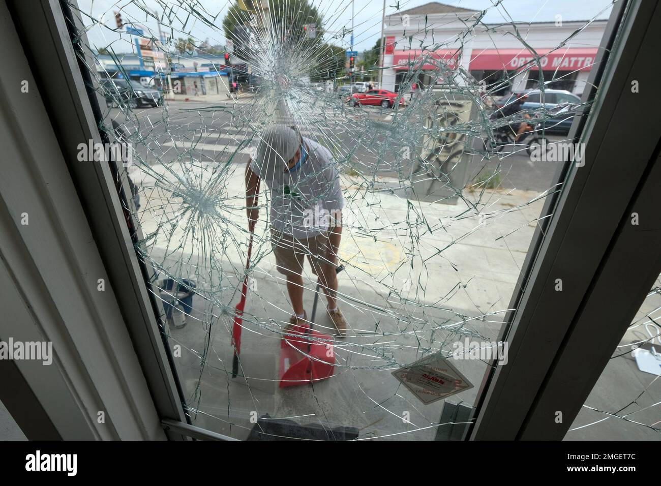 A volunteer sweeps up the broken glass behind a shattered store glass ...