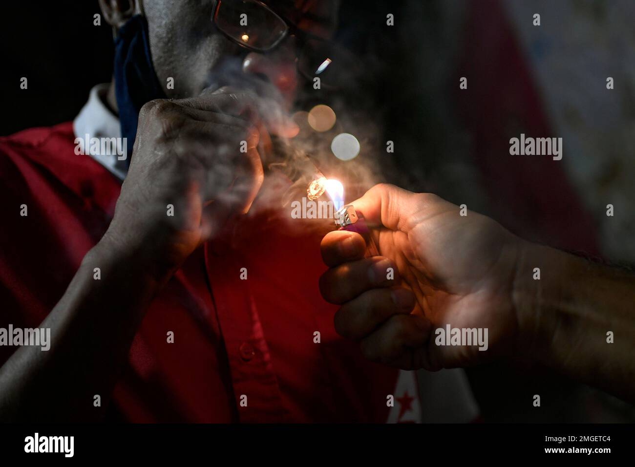 A man lights a cigar to symbolically purify his soul during an ...