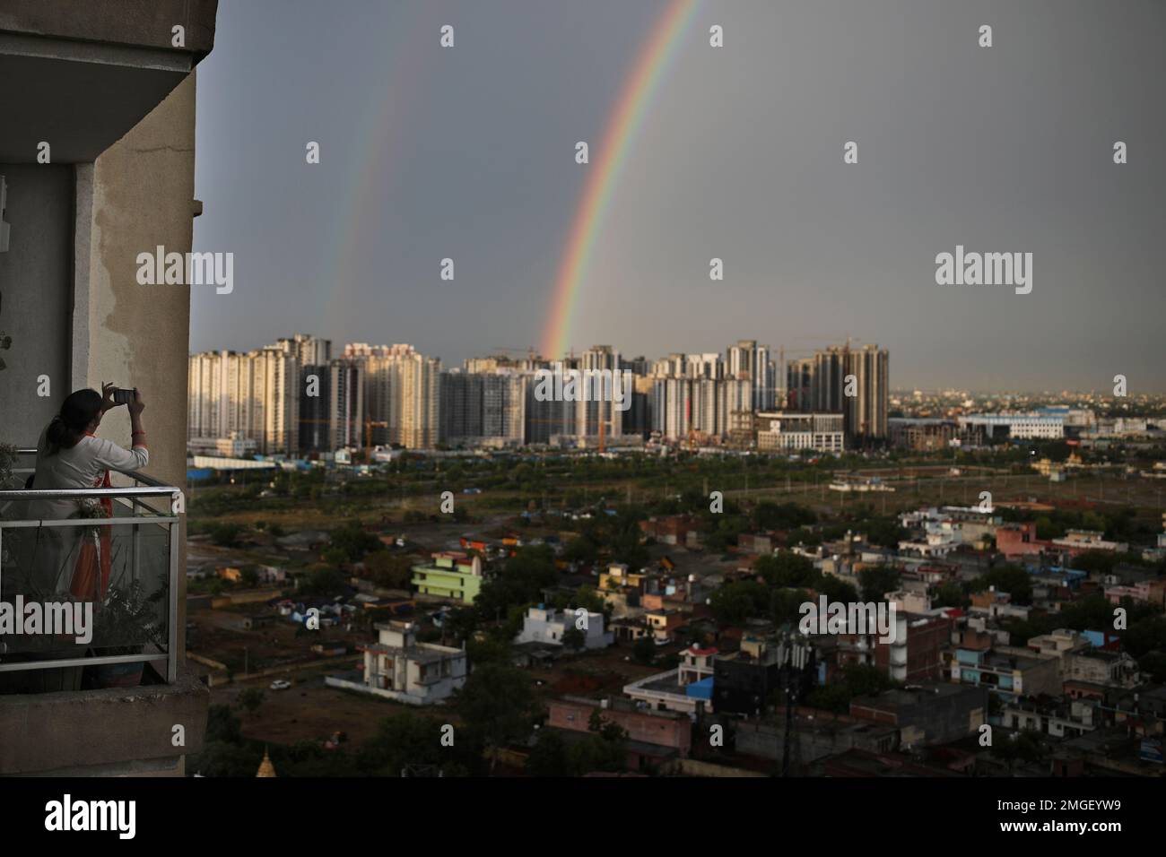 An Indian woman photographs a rainbow from her balcony as it appears on ...