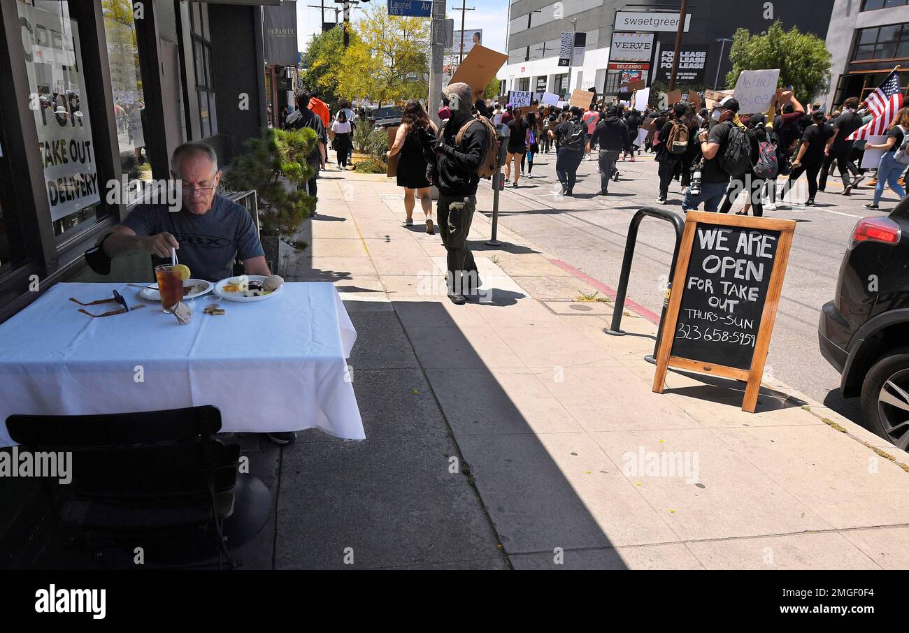 A man eats lunch as demonstrators walk along 3rd street during a ...
