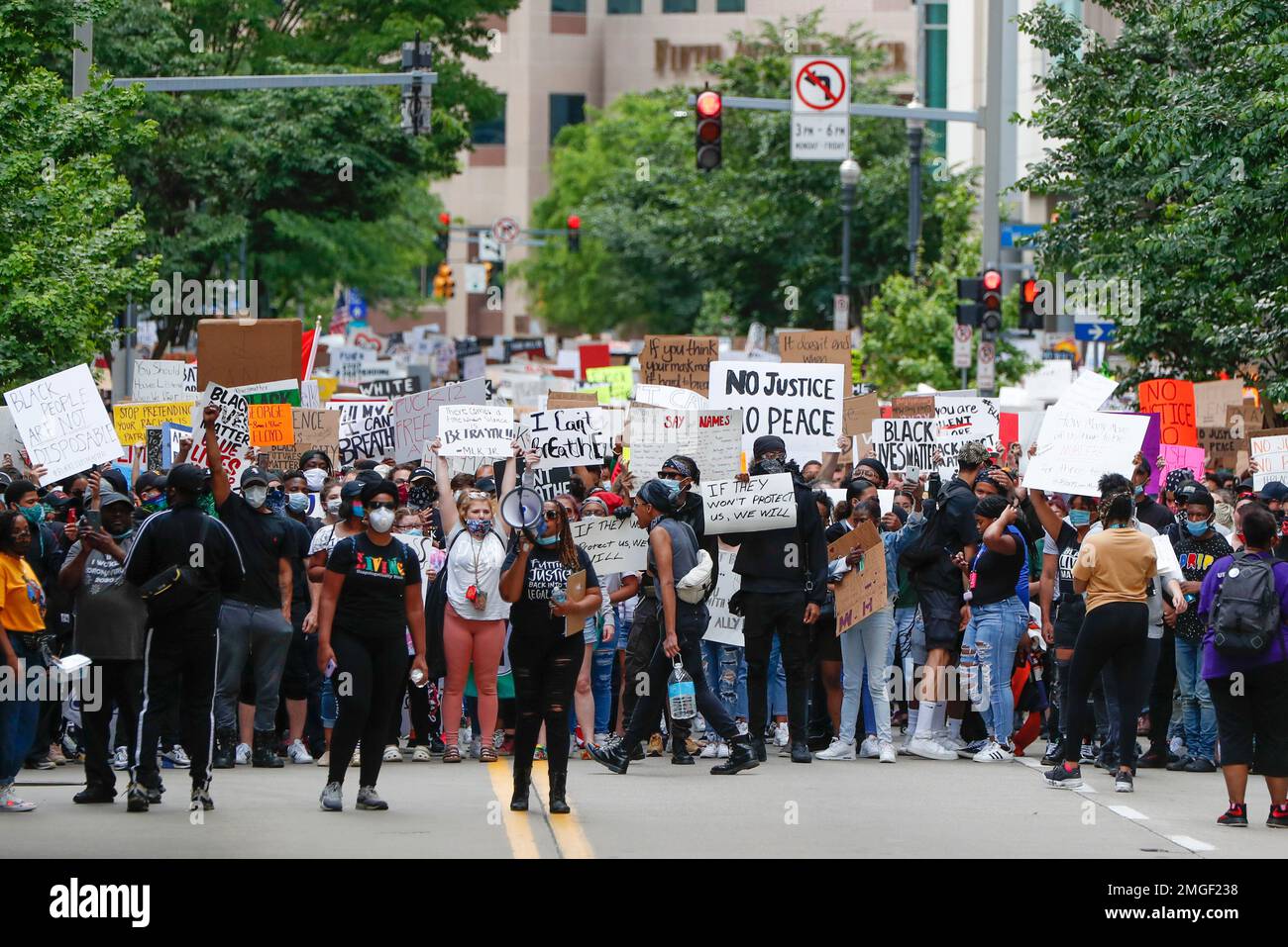 Demonstrators carry signs as they march up Fifth Avenue in Pittsburgh ...