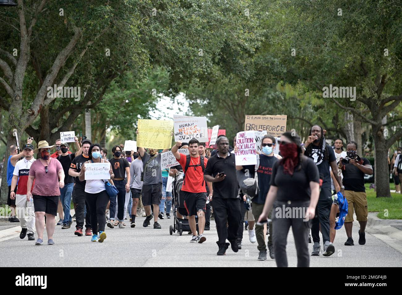 Protesters carry signs and march in front of a townhouse owned by ...