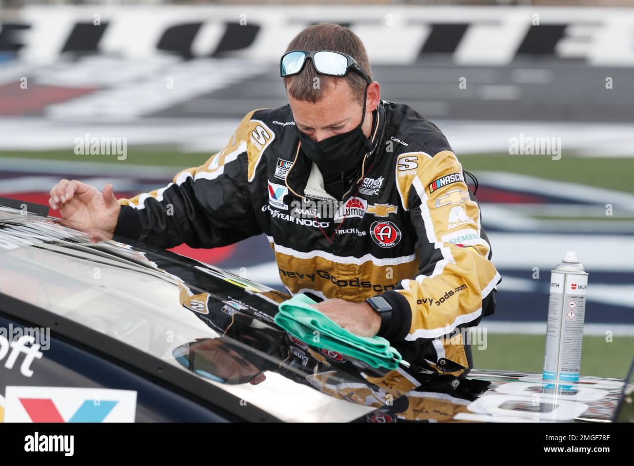 A crew member for driver Alex Bowman cleans the car's rear window ...