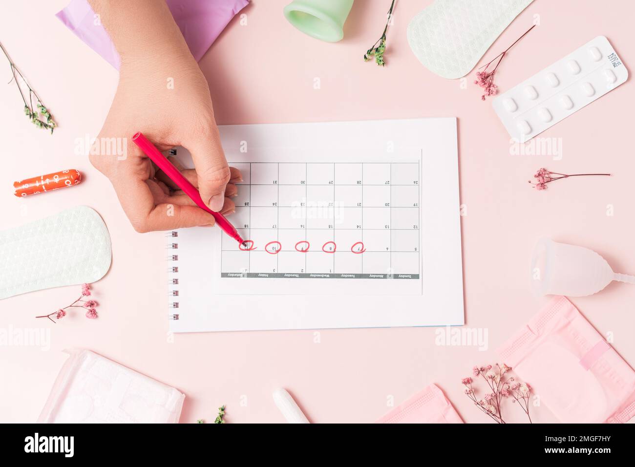 Lady marks with red felt-tip pen in the calendar the menstrual cycle on ...
