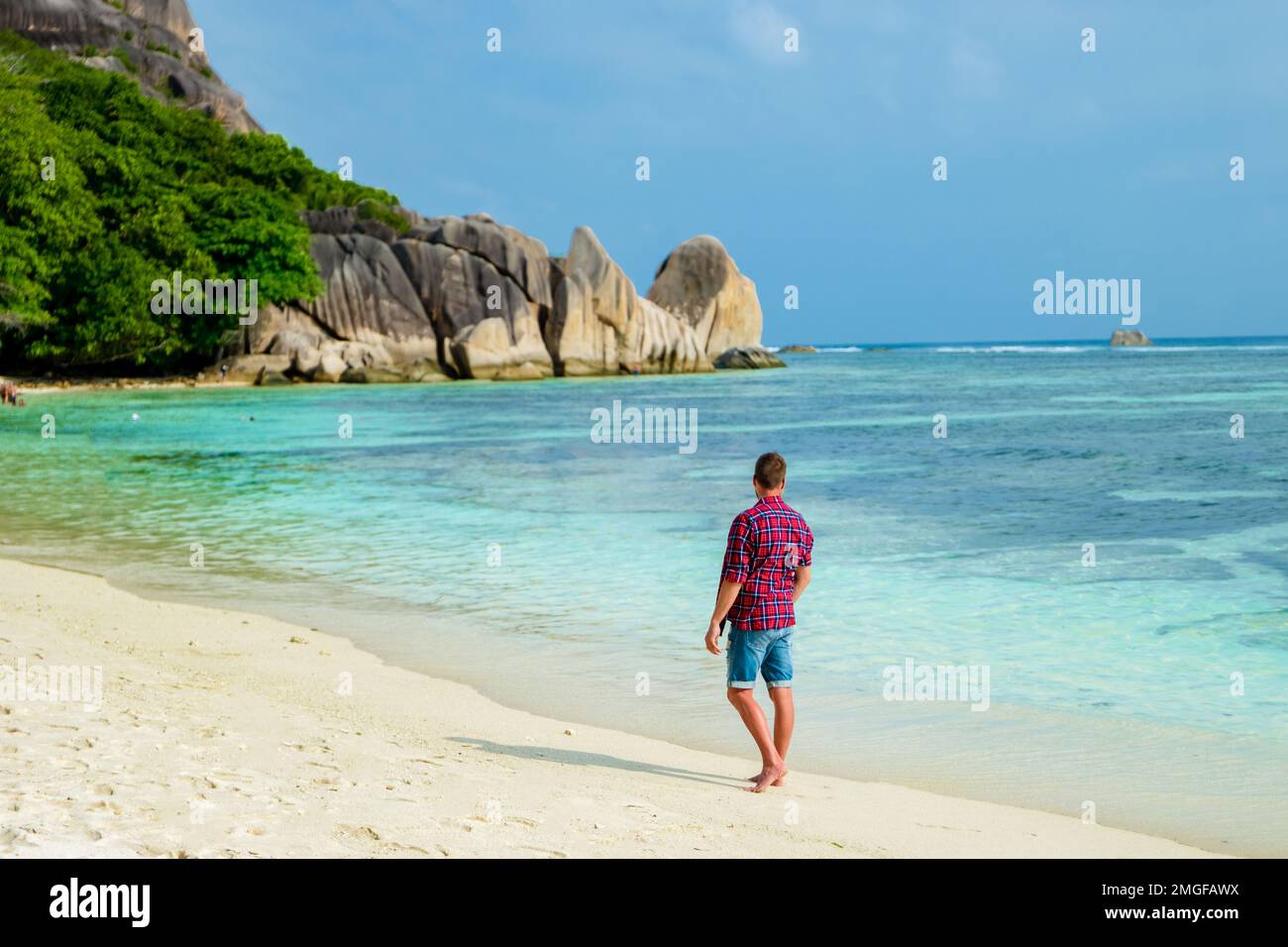 Young men walking at a white tropical beach Anse Source d'Argent beach ...