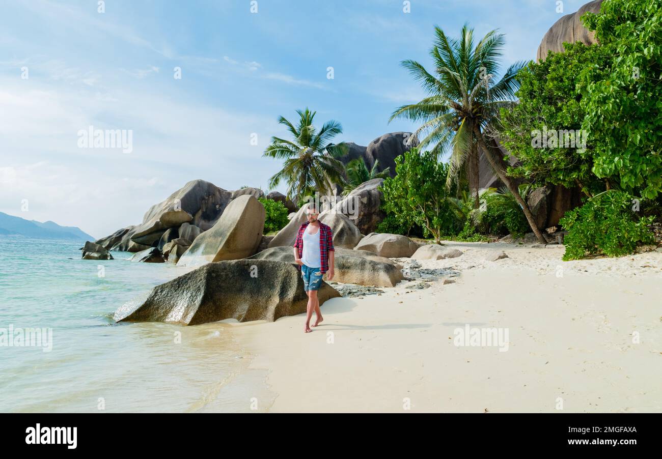 Young men walking at a white tropical beach Anse Source d'Argent beach ...