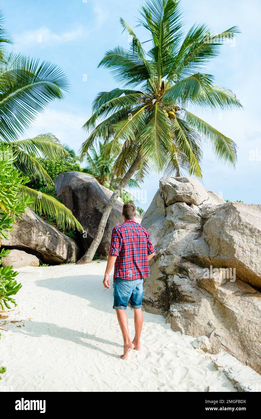 Young men walking at a white tropical beach Anse Source d'Argent beach ...