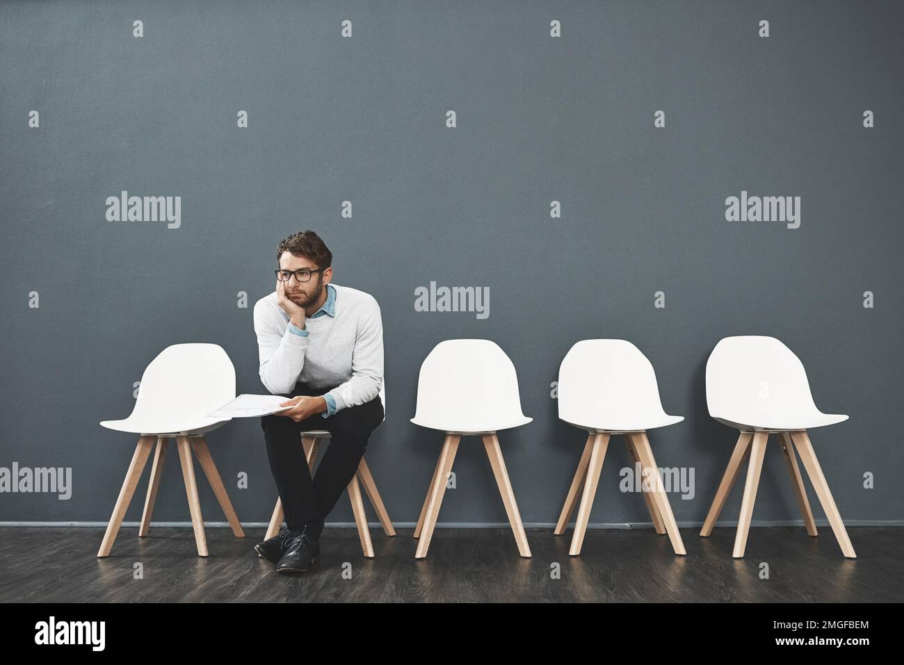 Waiting it out. a young man waiting in line for a job interview Stock ...