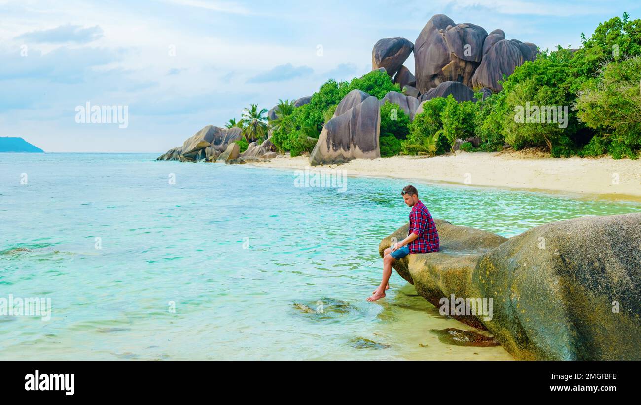 Young men at a white tropical beach Anse Source d'Argent beach La Digue ...