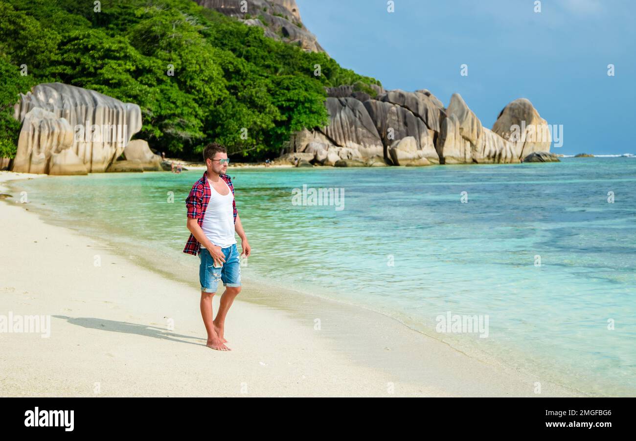 Young men walking at a white tropical beach Anse Source d'Argent beach ...