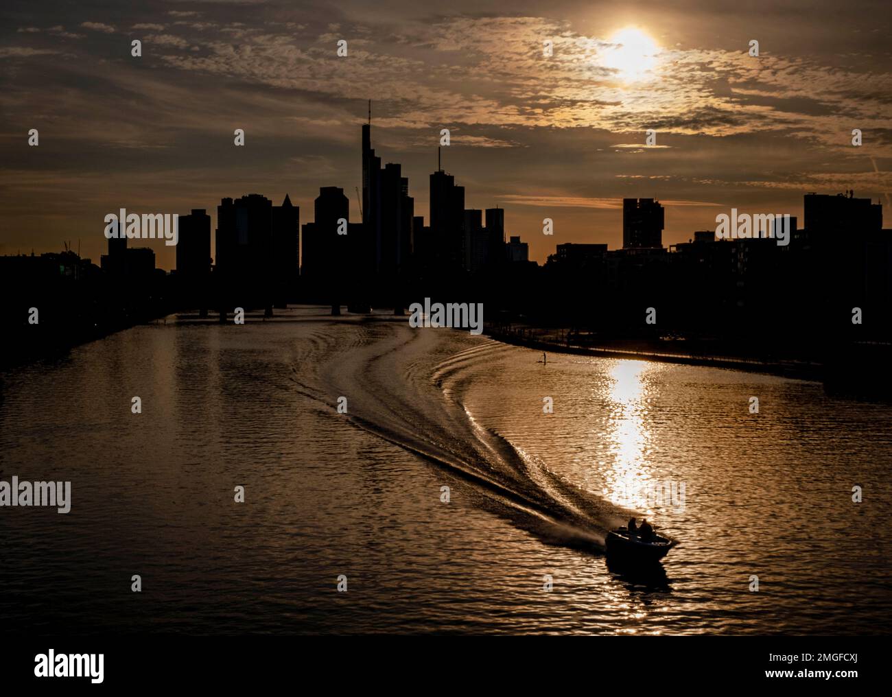 A motor boat speeds over the river Main with the buildings of the ...