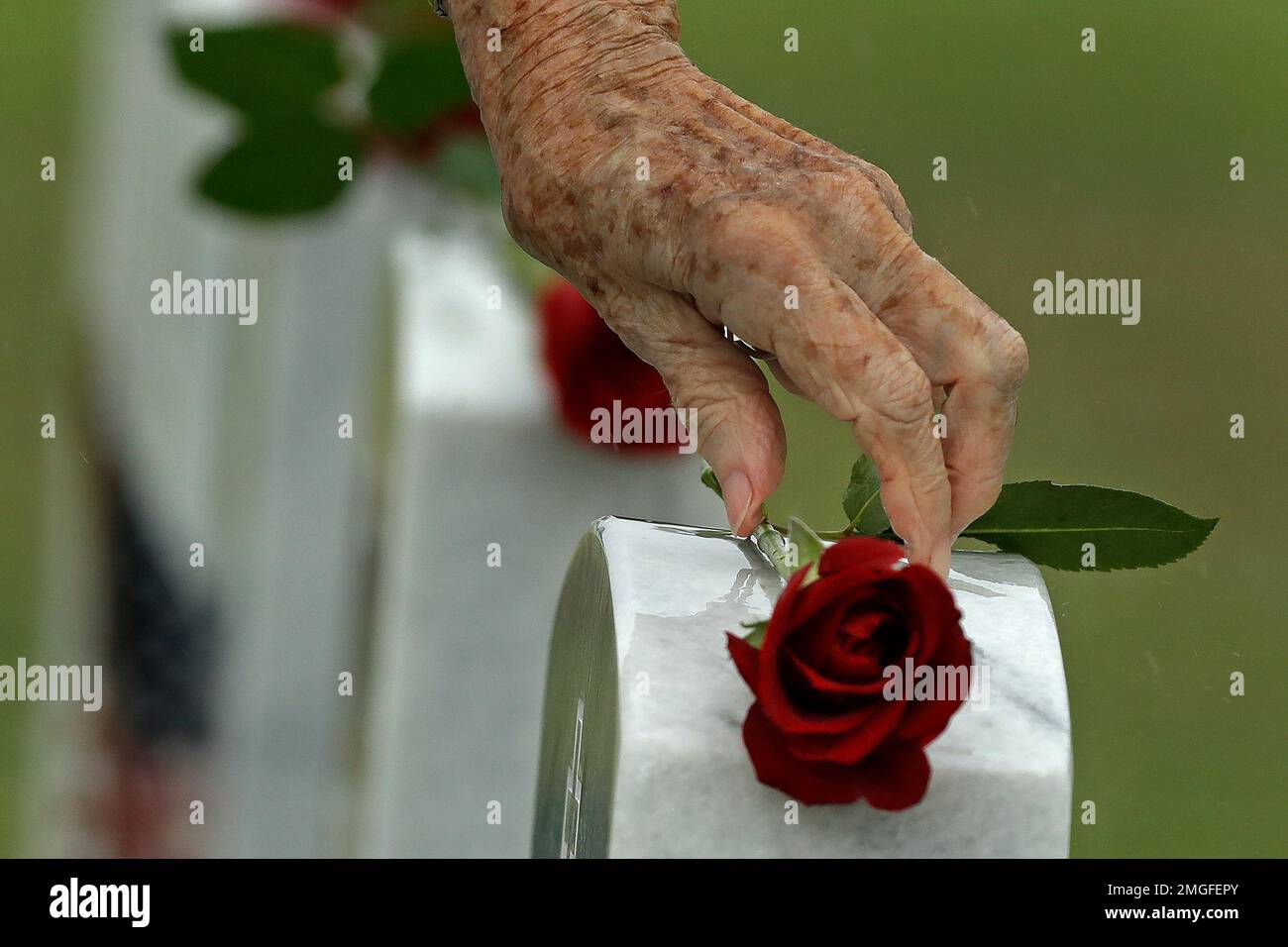 A woman places a rose on a tombstone for Memorial Day, Monday, May 25 ...