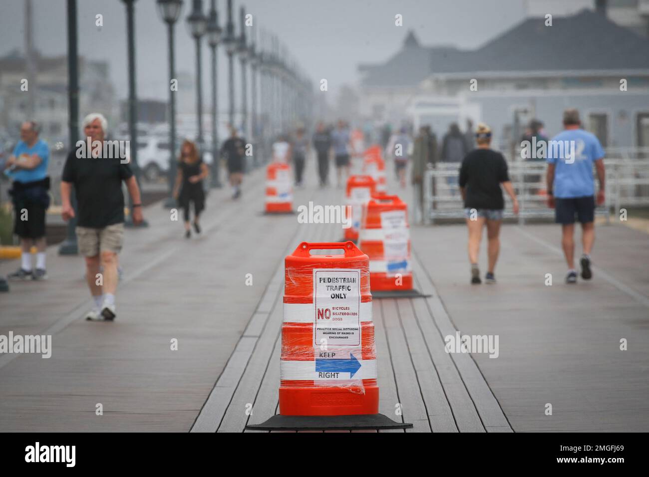 Peple walk along a boardwalk at a mostly empty beach Saturday, May 23 ...
