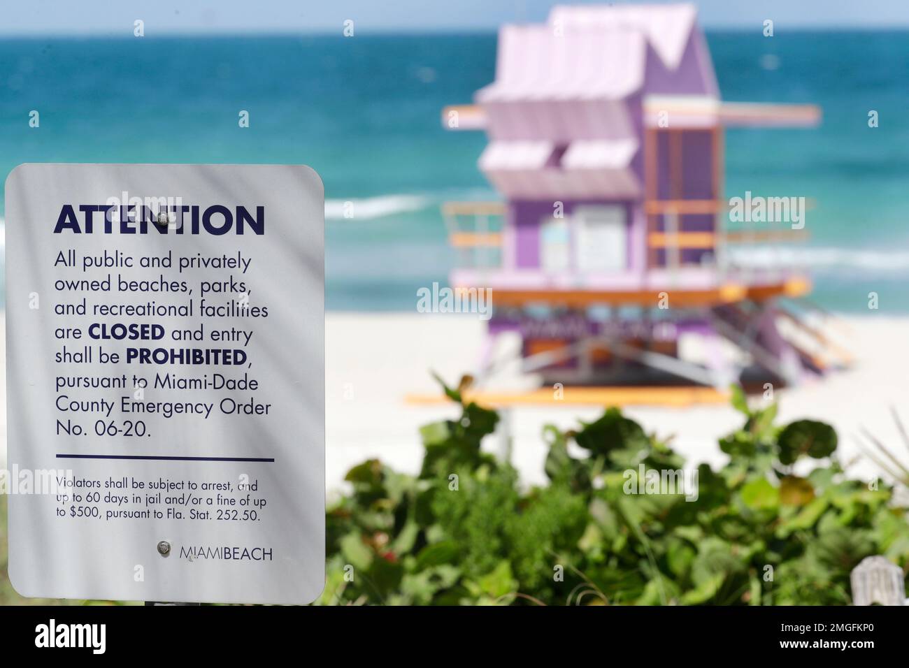 A sign stating that the beaches are closed is shown near a lifeguard ...