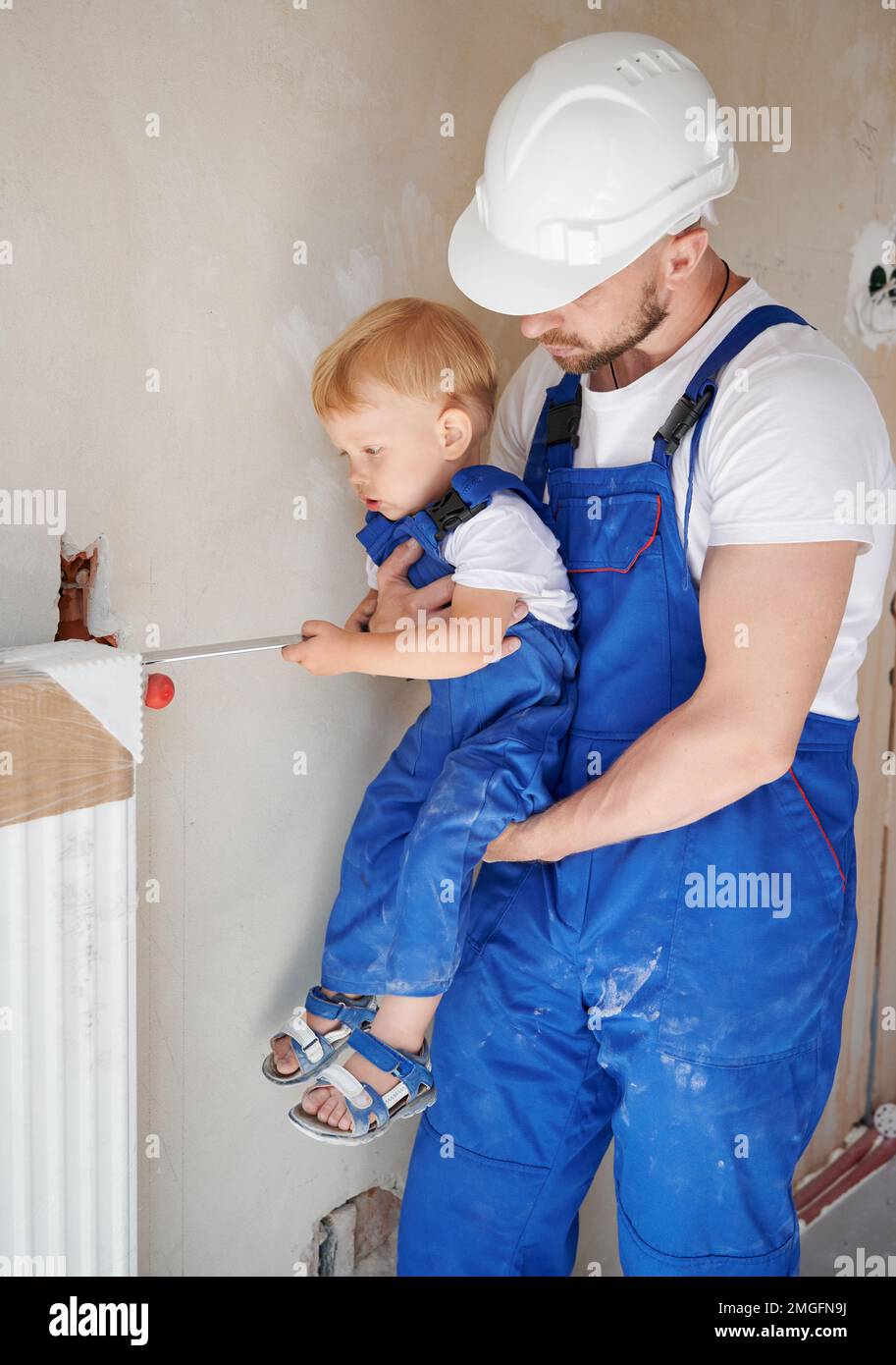 Adorable child using construction tool while installing heating ...