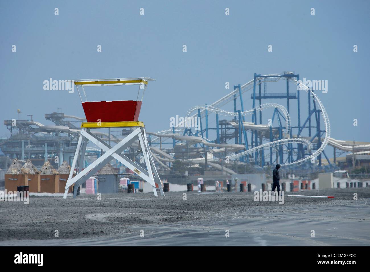 A man walks near an empty lifeguard tower along the beach, Thursday ...