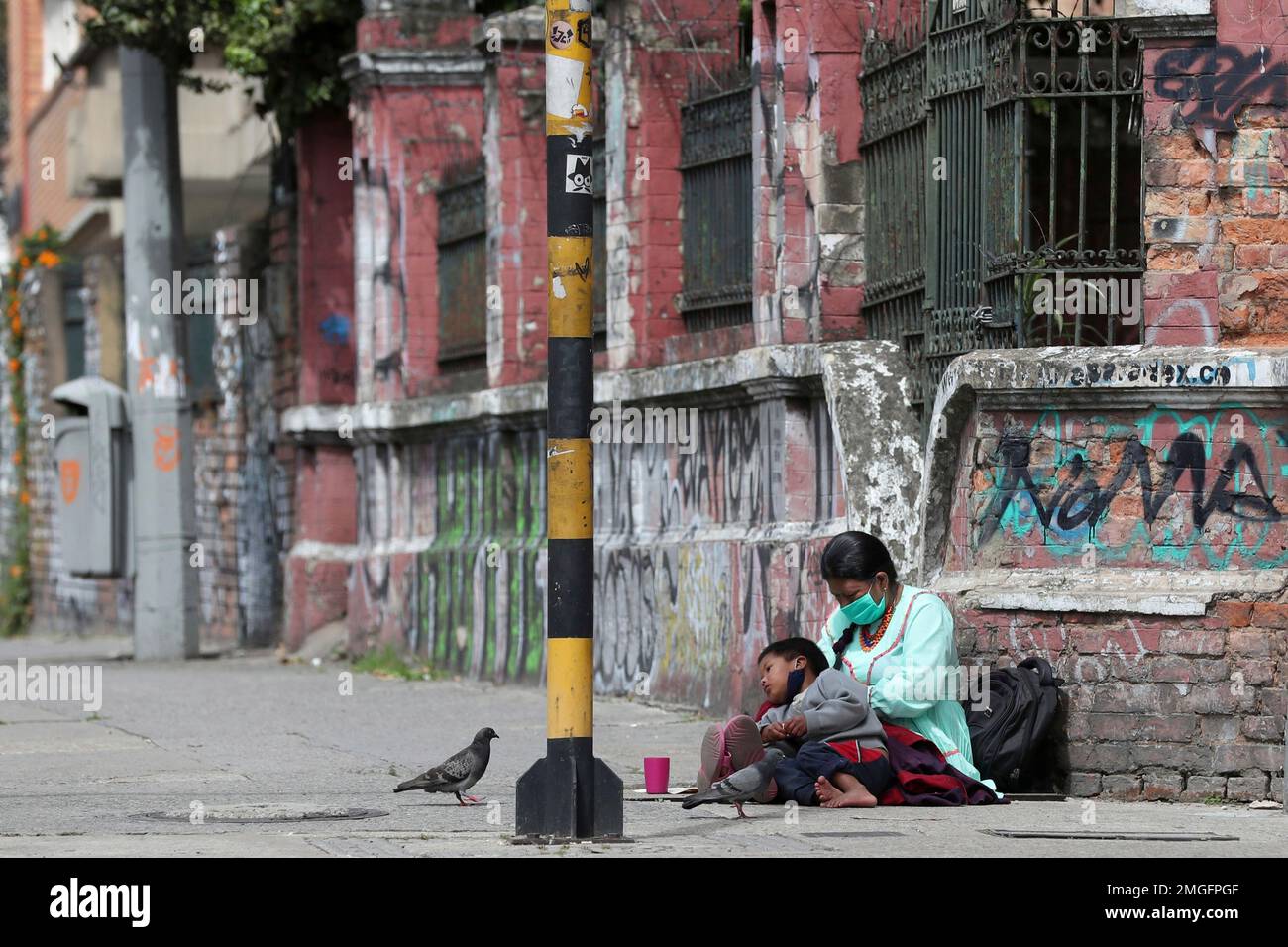 An indigenous women and her son sit on the sidewalk as they beg during ...