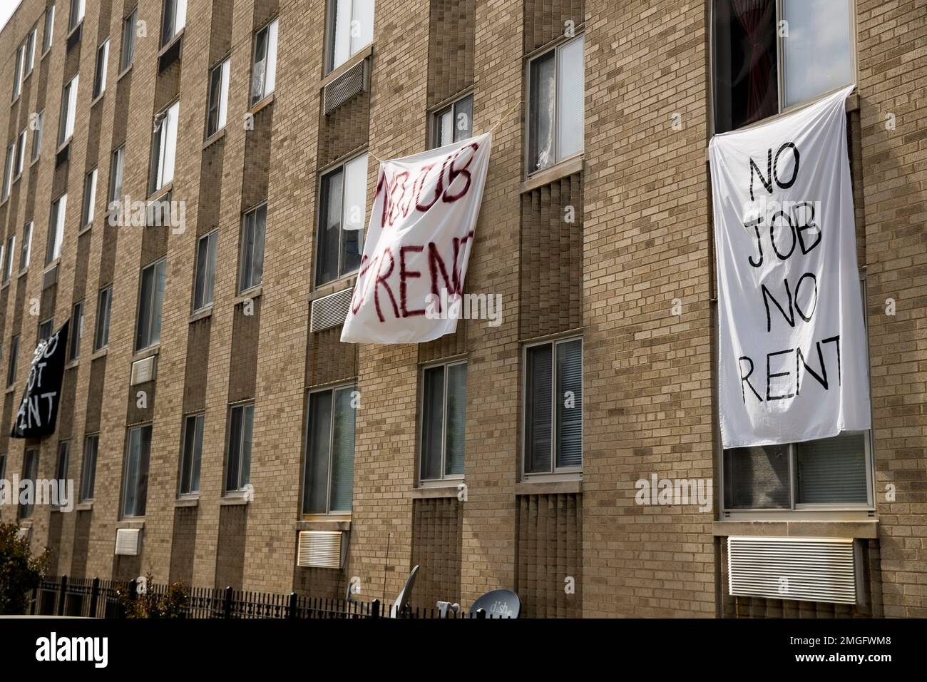 Signs reading "No Job No Rent" hang from the windows of an apartment ...