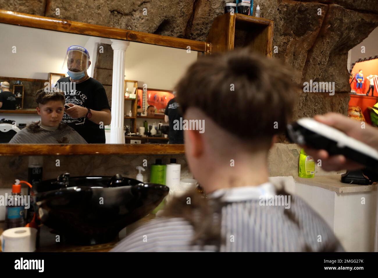 A boy gets his hair cut at the barber shop Bulli, in Rome, Italy ...