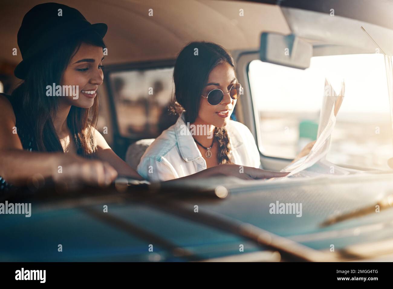 Off to see the world. two friends reading a map on their road trip ...