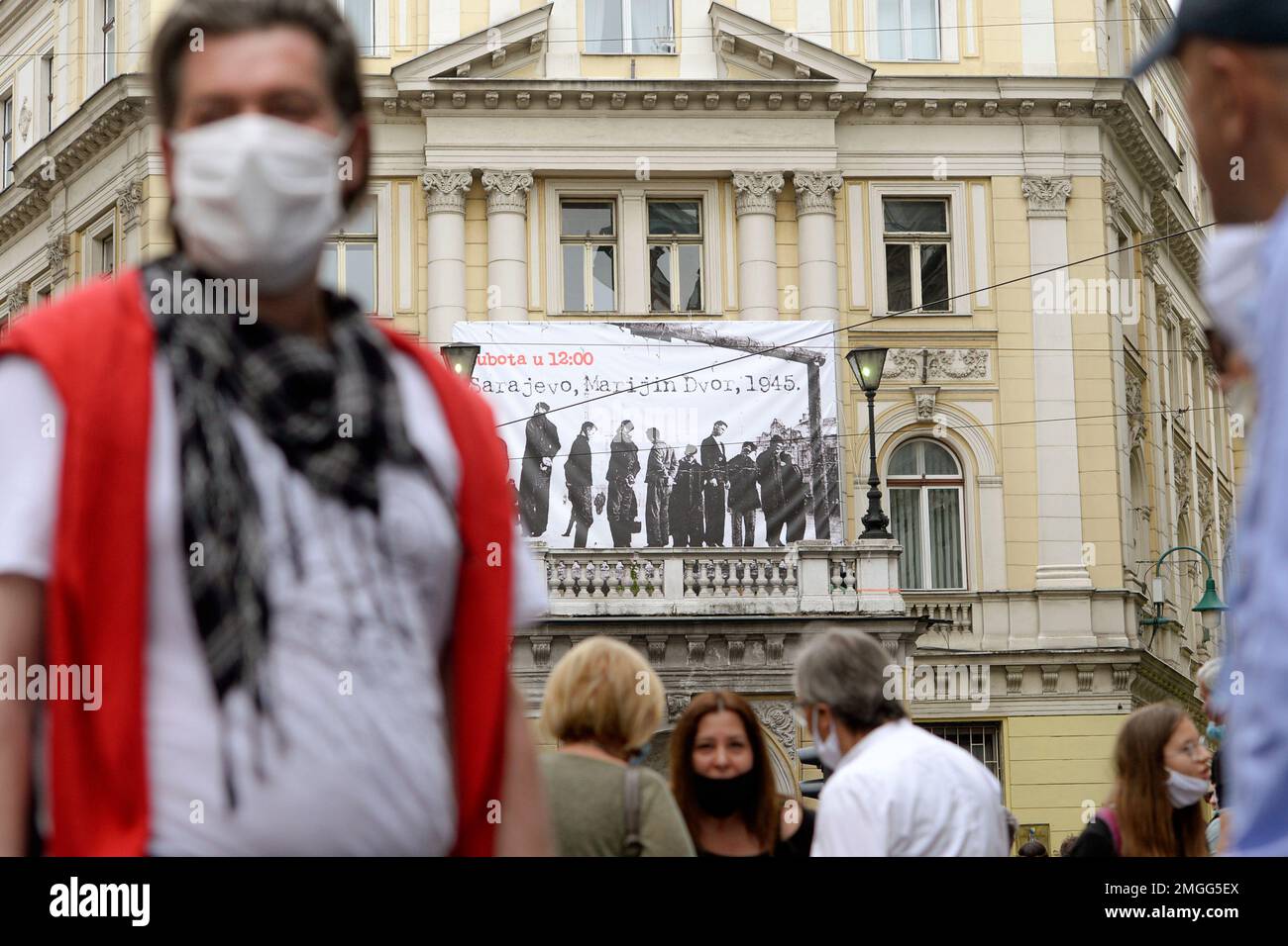 People walk backdropped by a banner showing victims executed by hanging ...