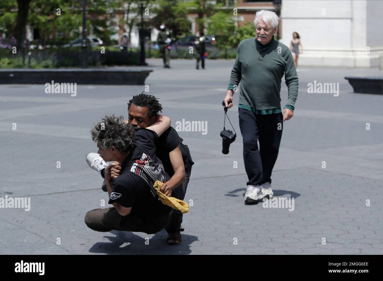 A man watches as two men fight in Washington Square Park Friday, May 15 ...
