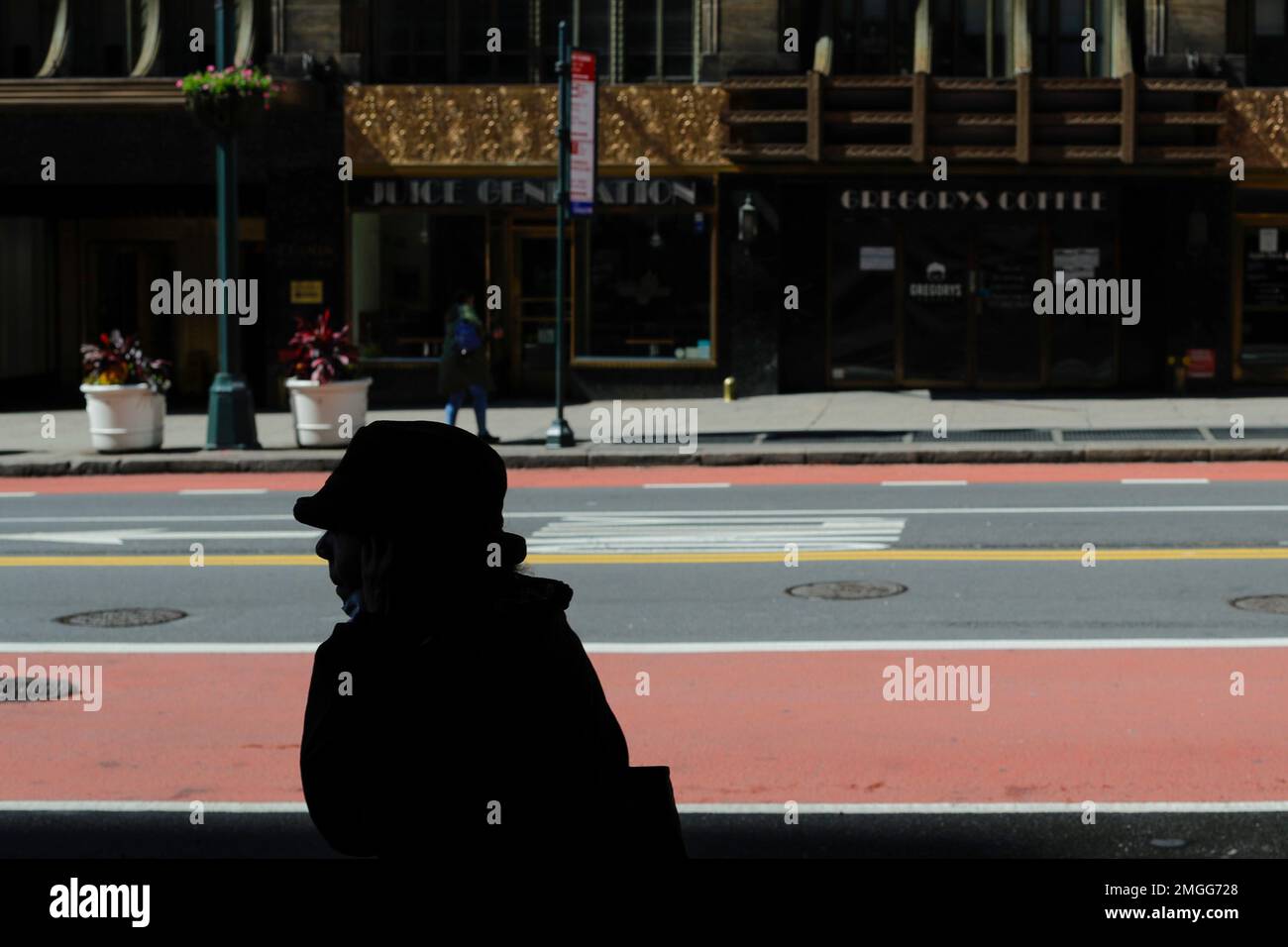 Pedestrians pass closed businesses as they walk along an almost empty ...