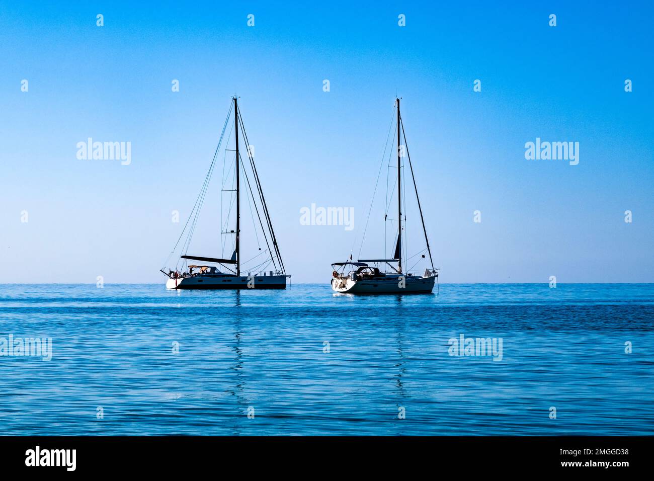 Two sailboats anchor off the coast of the the medieval town of Cefalu ...