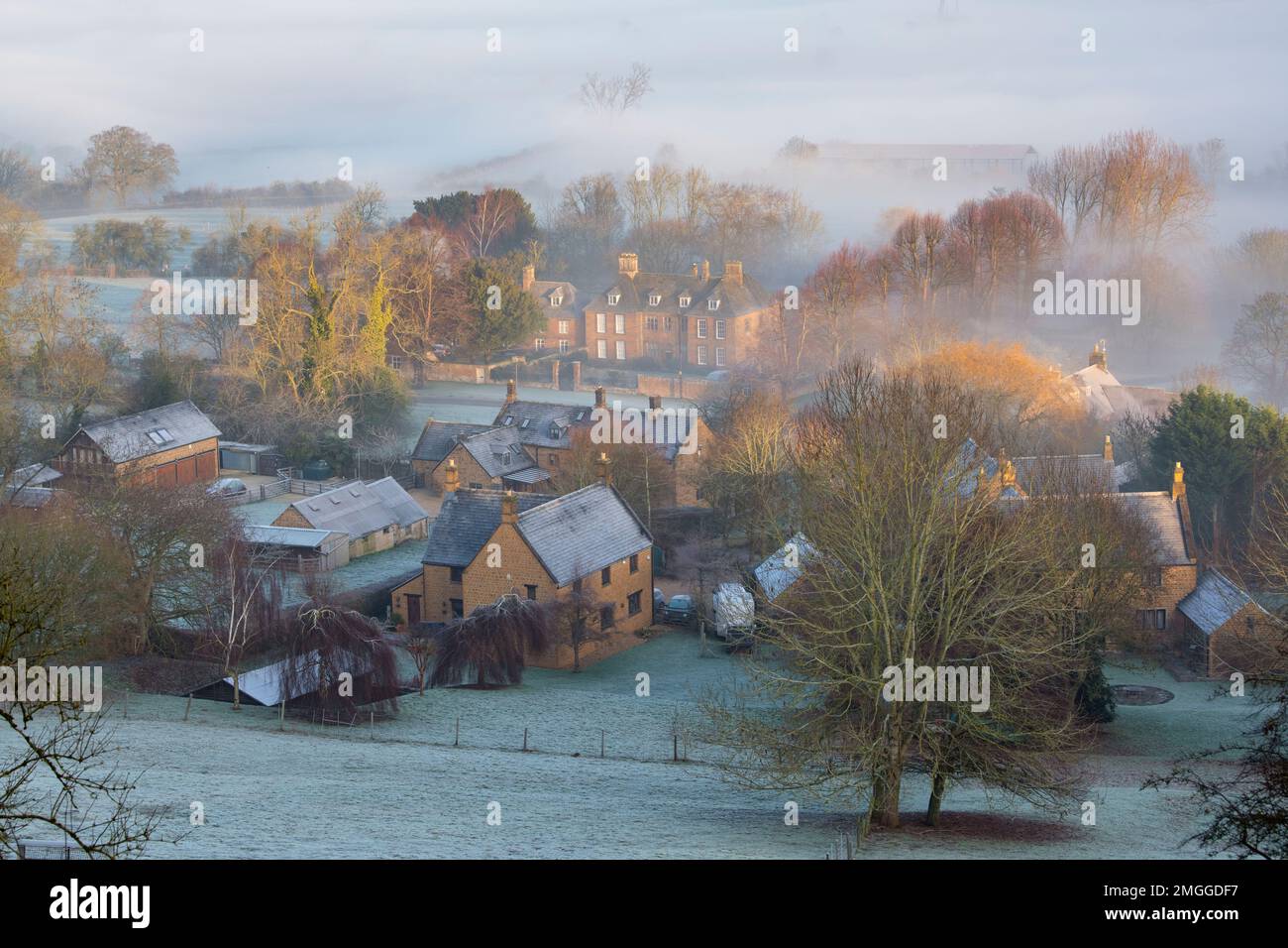 Winter morning sunlight over a foggy frosty Arlescote village in the ...