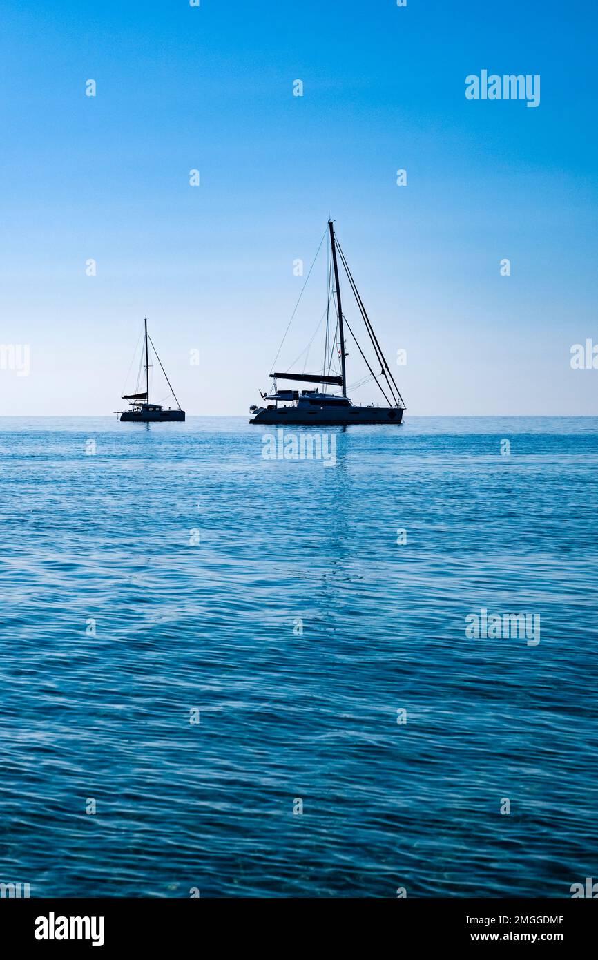 Two sailboats anchor off the coast of the the medieval town of Cefalu ...