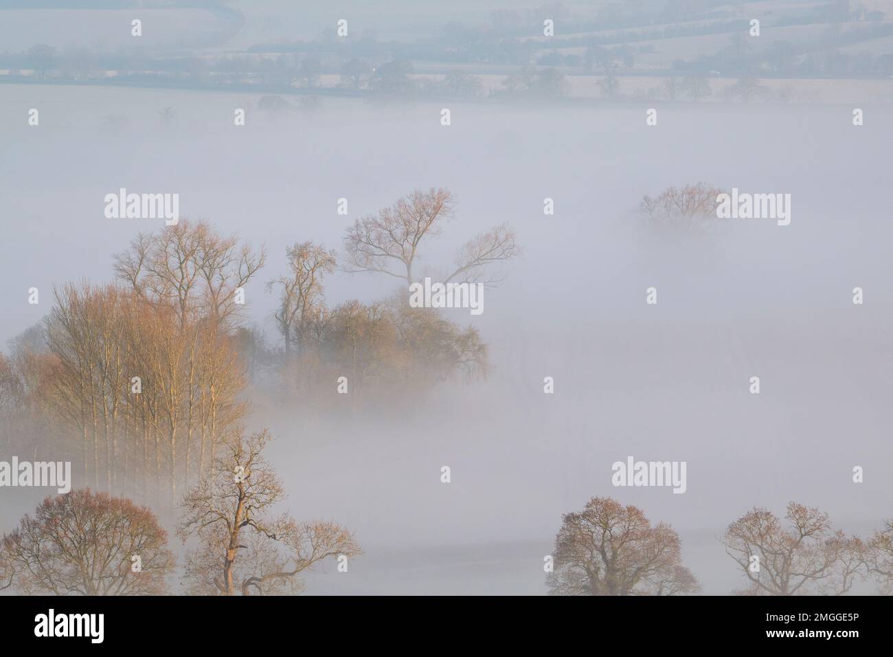 Winter morning sunlight over a foggy frosty Arlescote in the ...