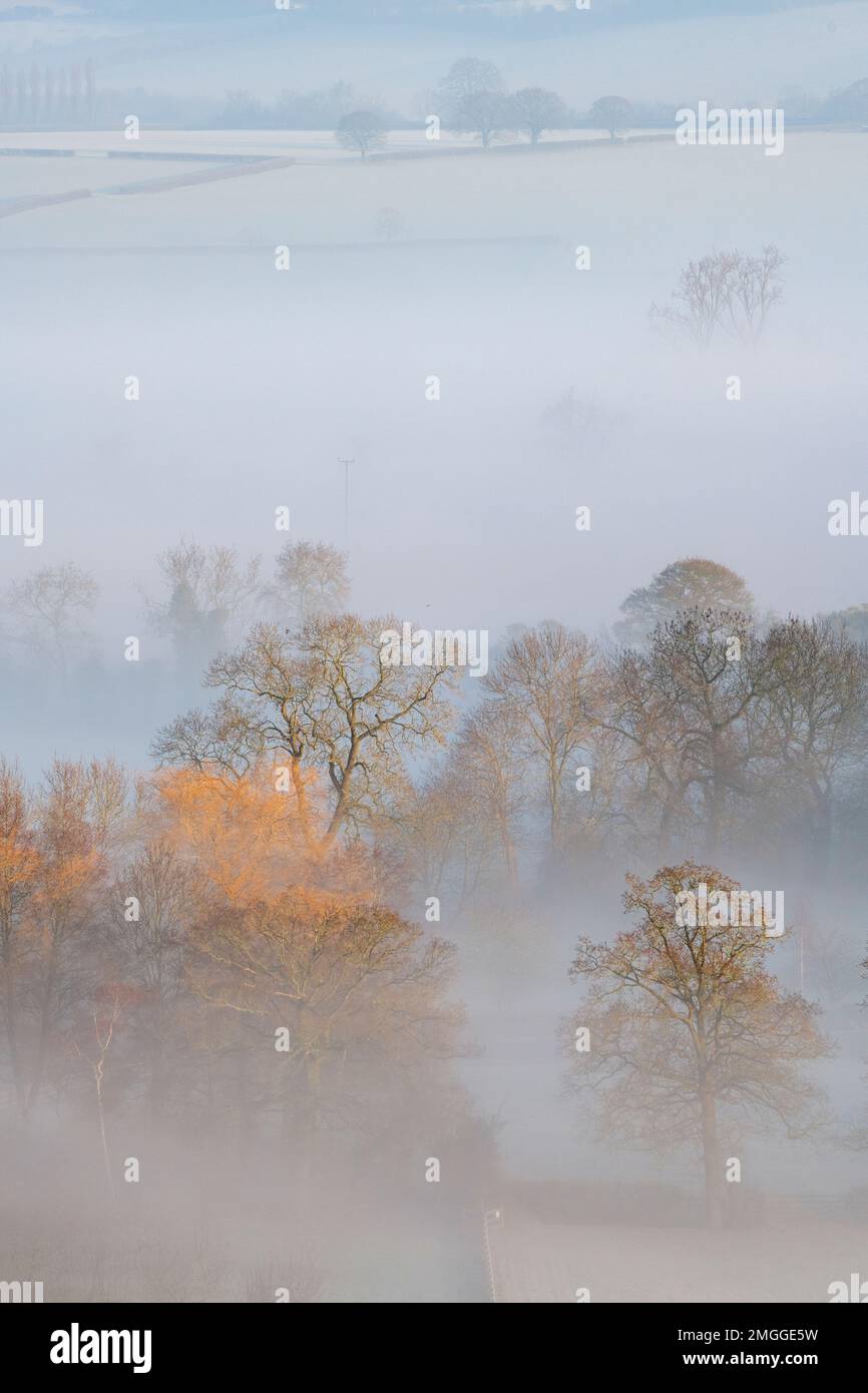 Winter morning sunlight over a foggy frosty Arlescote in the ...