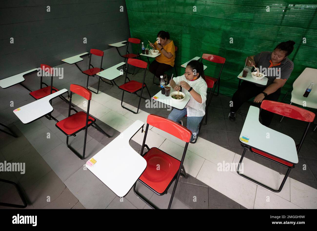 A noodle shop uses table arm chairs for social distancing to help curb ...