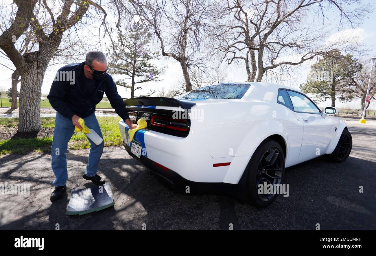 John Cummings wears a face mask to put a coat of wax on his 2019 Dodge ...