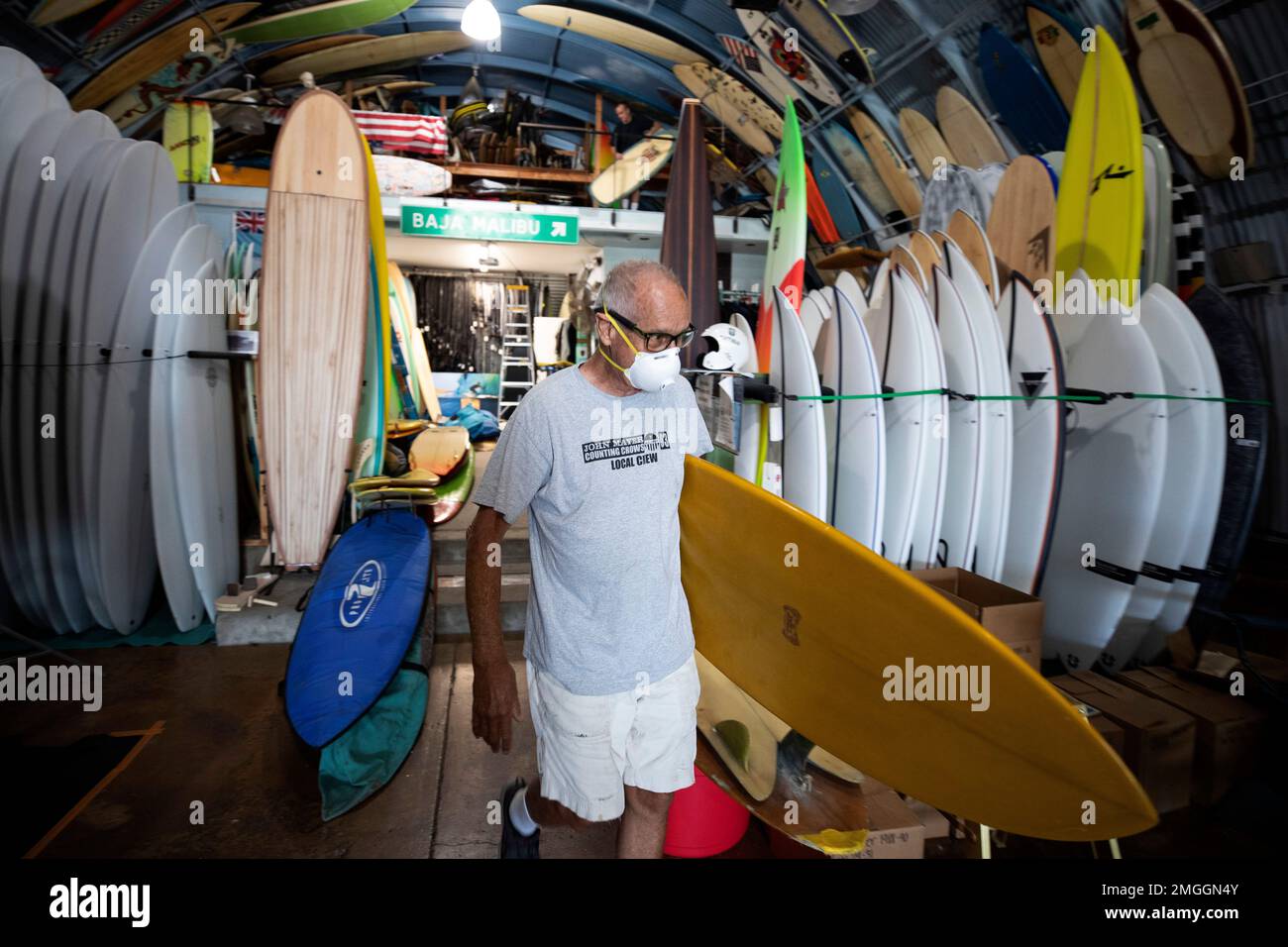 Surf shop worker Scat wears a mask while carrying a surfboard as Bird's ...