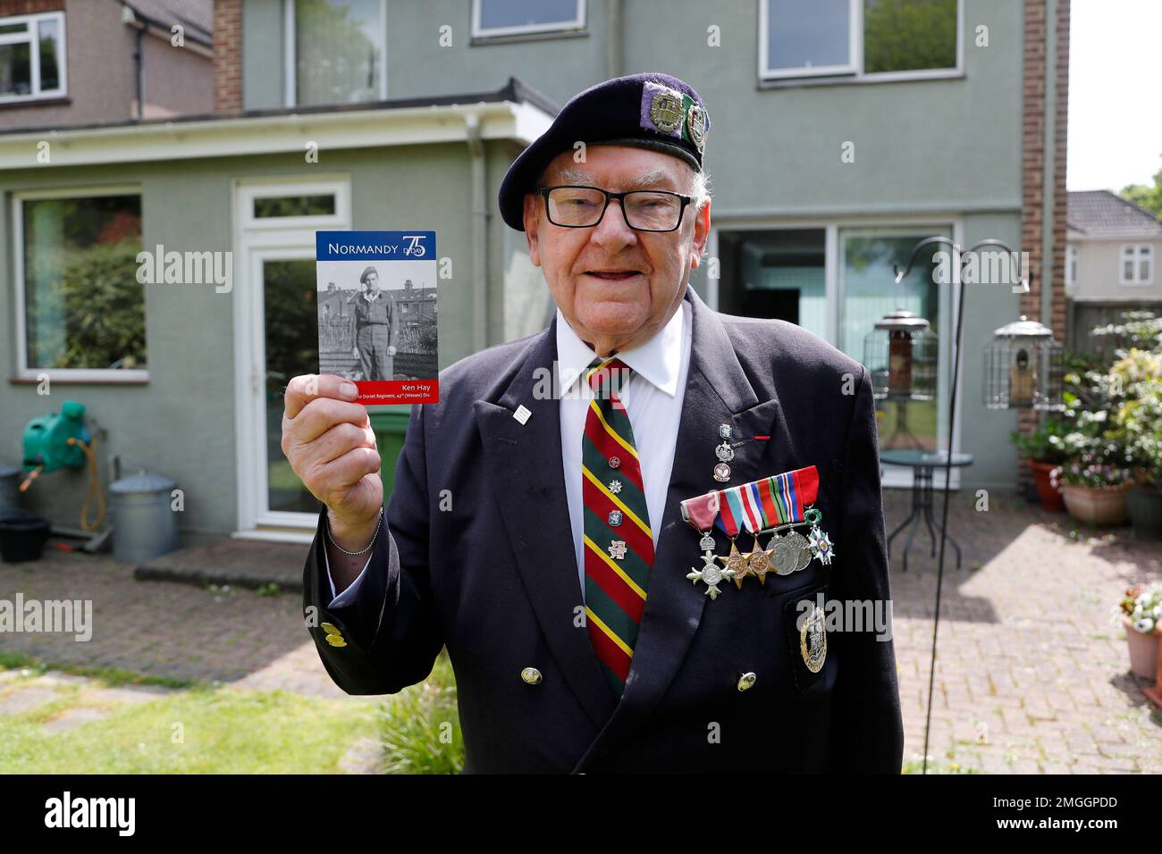 World War II veteran Ken Hay poses in front of his house with a picture ...