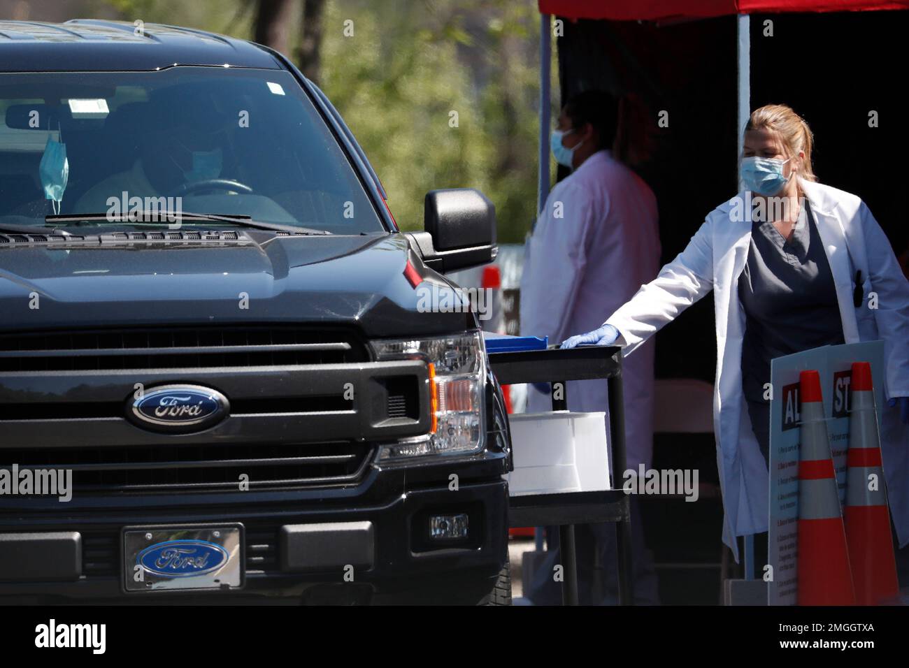 Cars approach a temporary COVID-19 drive-thru test site where patients ...