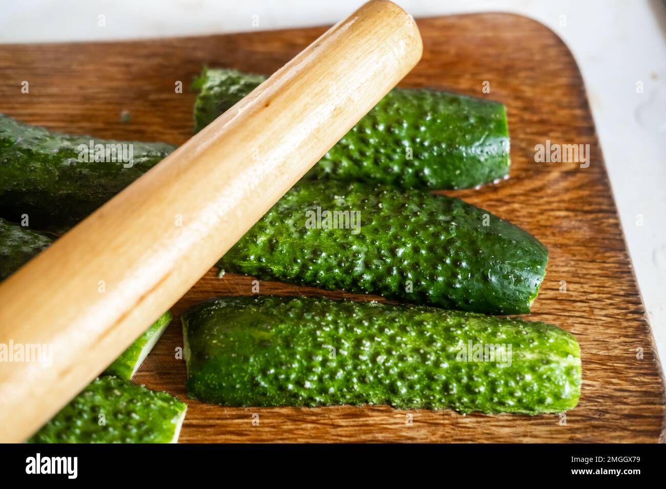 Preparation of beaten cucumbers. Halves of fresh cucumbers on a cutting ...