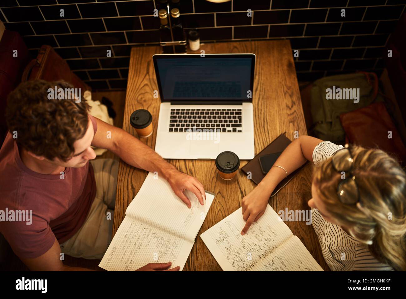 Time for a cafe study session. High angle shot of two unidentifiable students having a study ...