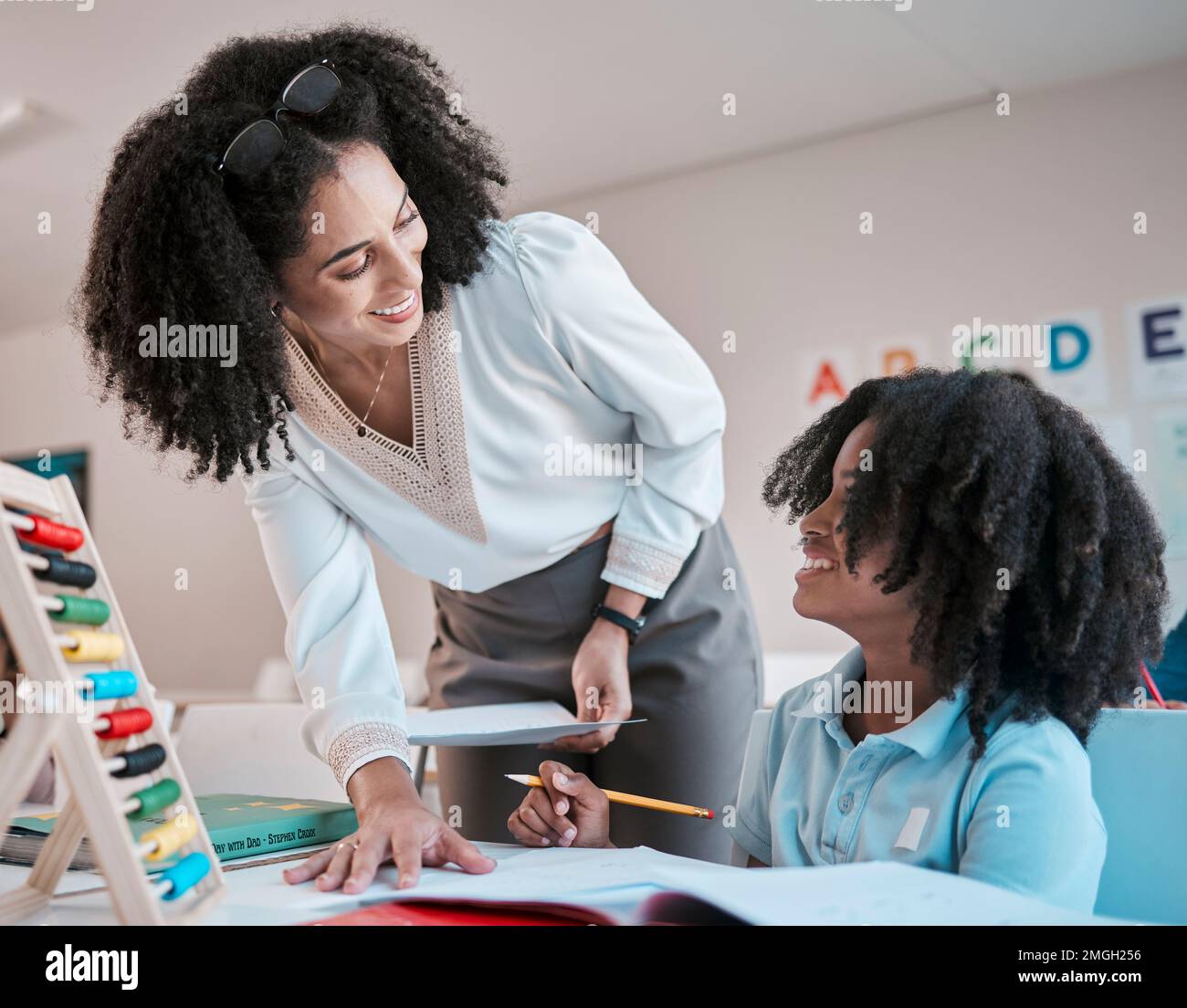 Female teacher in classroom, helping girl student assessment and ...